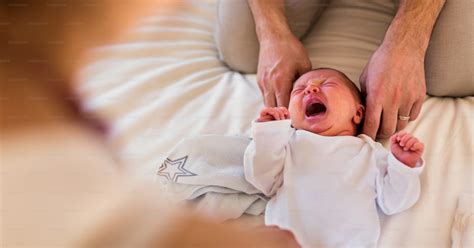 집에서 알아볼 수 없는 젊은 부모들이 침대에서 귀여운 딸을 차려 입고 어린 소녀가 울고 있습니다 사진 Unsplash의 영감 이미지