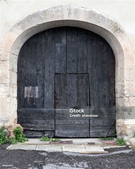 프랑스에서 집의 고 대 석회암 벽에 아주 오래 된 어두운 아치형된 나무 문 0명에 대한 스톡 사진 및 기타 이미지 0명