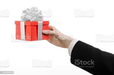 축 하와 선물의 테마 흰색 리본 및 활 스튜디오에서 흰색 배경에 고립 된 가장 아름 다운 선물 빨간색 상자에 싸여 독점적인 선물을 들고 검은 양복에 남자 기념일에 대한 스톡