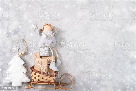 크리스마스와 새해 어린이 구성 산타의 나무 썰매와 회색 콘크리트 배경에 있는 흰색 나무의 선물 상자에 크리스마스 천사 플랫 플랫 복사 공간 인사말 카드 모형입니다 썰매