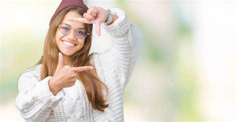 손으로 만드는 프레임 및 행복 한 얼굴로 손가락을 웃 고 고립 된 배경 위에 선글라스를 착용 하는 젊은 아름 다운 갈색 머리 Hipster 여자 창의력과 사진 개념입니다