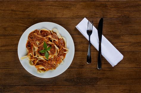 볼로네즈 소스와 바질 잎을 곁들인 파스타 타글리아텔 흰색 냅킨에 포크와 칼 마카로니는 전 세계적으로 인기가 있습니다 상단 보기 사진 0명에 대한 스톡 사진 및 기타 이미지