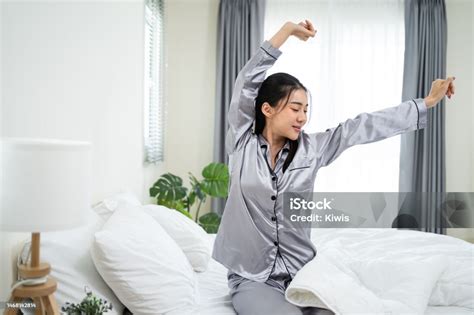 잠옷에 아시아 아름 다운 여자 행복으로 아침에 일어나 매력적인 젊은 여성은 웃고 행복을 느끼고 집에서 침실에서 침대에서 자고 나서 몸을 스트레칭합니다 30 34세에 대한