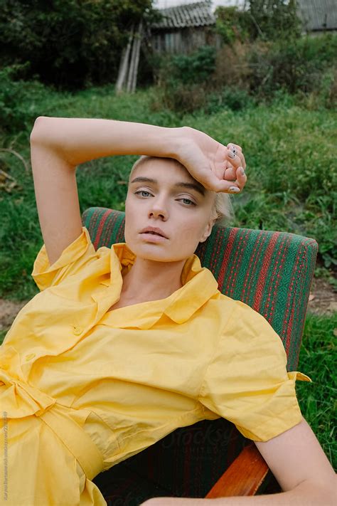 Beautiful And Stylish Girl In A Yellow Retro Dress Who Sits In A Chair By Stocksy Contributor