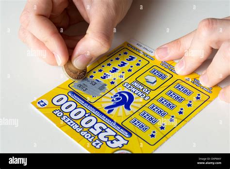 Hand Scratching A National Lottery Scratchcard With Coin England Uk