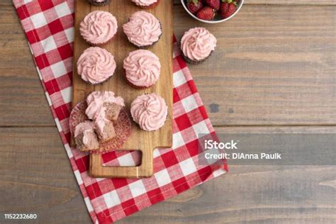 하나 깨진 오픈 나무 절단 보드에 집에서 만든 딸기 컵 케이크 신선한 딸기의 그릇 나무 테이블에 빨간색과 흰색 체크 냅킨 냅킨에