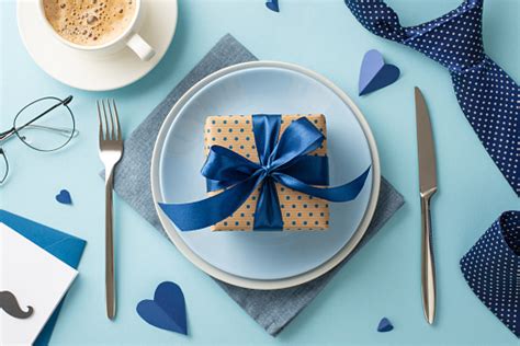 파스텔 블루 배경에 접시 커피 머그잔 수저 냅킨 리본 리본 넥타이 안경 우편 및 하트가 있는 선물 상자가 있는 멋진 아버지의 날