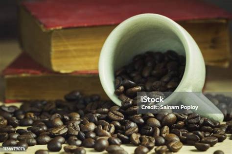 기울 어 진 세라믹 컵과 오래 된 책에 있는 커피 콩은 나무로 되는 테이블에 뒤에 놓았다 0명에 대한 스톡 사진 및 기타 이미지 0명 갈색 개념 Istock