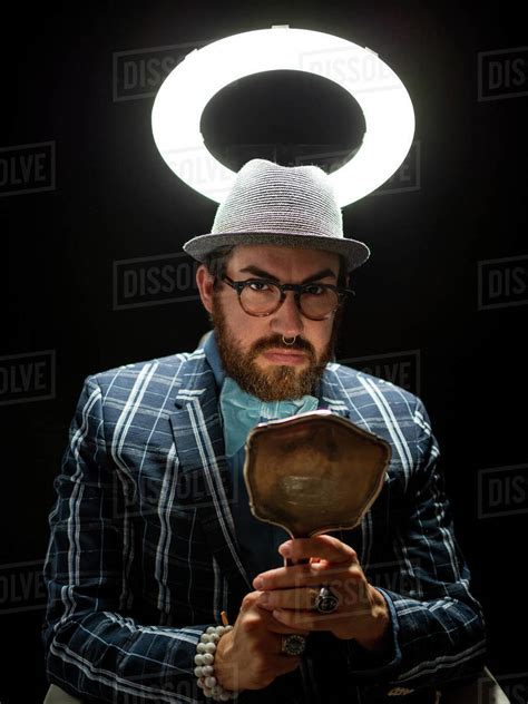 Smart Bearded Man In Glasses And Hat Admiring Reflection In Mirror Under Circle Light On Black