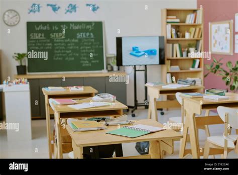 Well Organized Classroom Setup With Study Materials Neatly Arranged On Tables And A Chalkboard