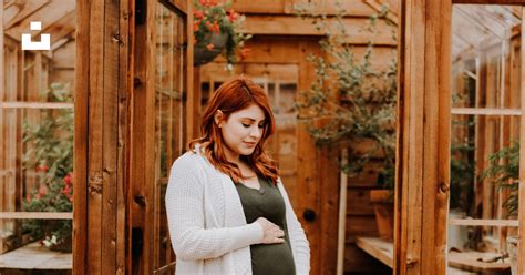 정원 헛간 근처에 서서 배를 잡고 있는 임산부 사진 Unsplash의 무료 임신 이미지