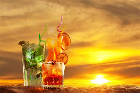 해변에서 오렌지와 녹색 칵테일 얼음 오렌지 민트 라임이 있는 알코올 음료 배경에 일몰 바다와 하늘 유리 근처의 텍스트를 위한 공간과 여유 공간을 복사합니다 0명에 대한 스톡