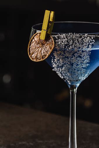 칵테일 항공 진 레몬 주스 마라스키노 비올레트 리큐어와 함께 마십니다 라임 칩과 코코넛 부스러기로 장식합니다 닫아 어두운 배경에