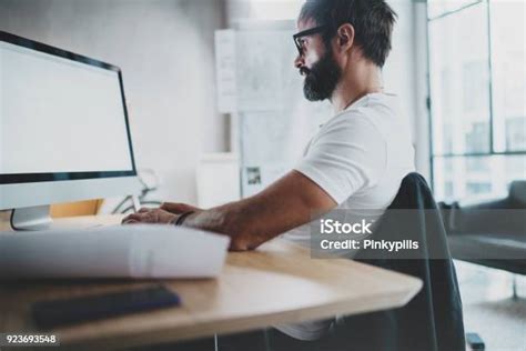 젊은 수염 눈 안경을 현대 로프트 스튜디오데스크톱 컴퓨터와 사무실에서 일 하는 전문 건축가 화이트 빈 화면을 표시 합니다 흐리게