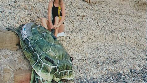 Alla Inflates A Large Inflatable Turtle On The Beach With A Hand Pump