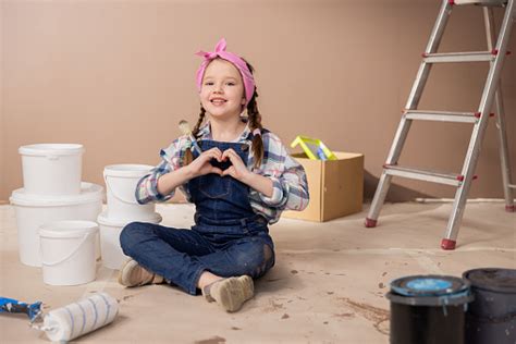 웃는 소녀가 손가락으로 배열 된 심장을 보여줍니다 어린이는 페인트 캔 주위의 바닥에 앉아있는 새 아파트의 개조에 만족합니다 Diy에 대한 스톡 사진 및 기타 이미지 Istock