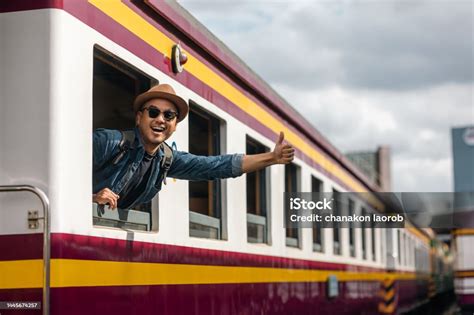 젊은 아시아 남자는 기차로 여행합니다 머리를 뻗어 기차 창문 밖으로 내밀었다 탐험가 백패커 도착 및 플랫폼 철도에서 출발 휴가 시간 휴일 주말에 자유 여행 관광에 대한 스톡