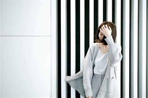 Premium Photo Smiling Woman With Hand In Hair Against Wall