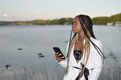 긴 검은 색과 금발 머리띠와 아프로 스타일의 검은 소녀는 배경에 호수와 헤드폰그녀의 전화를 사용하여 머리띠 땋은 머리에 대한 스톡 사진 및 기타 이미지 Istock