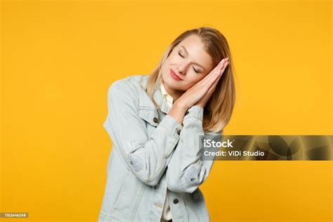 스튜디오에서 노란색 오렌지 벽 배경에 고립 뺨에서 접힌 손으로 데님 캐주얼 수 면에 편안한 예쁜 젊은 여자의 초상화 사람들 라이프 스타일 개념입니다 복사 공간을 모의 합니다