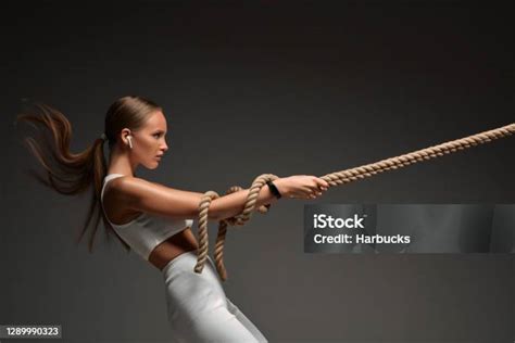 회색 배경에 고립 된 밧줄을 당기는 흰색 스포츠웨어에서 스포티 한 매력적인 여성의 측면 보기 20 24세에 대한 스톡 사진 및 기타 이미지 Istock