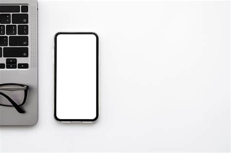 빈 모형 화면이있는 스마트 폰은 노트북 컴퓨터가있는 흰색 사무실 책상 테이블 위에 있습니다 복사 공간 플랫 레이가 있는 상단 뷰입니다 0명에 대한 스톡 사진 및 기타 이미지