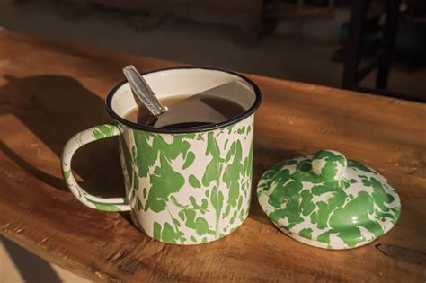 녹색 추상 패턴의 에나멜 철제 유리에 담긴 뜨거운 차 또는 커피 햇빛이 비치는 나무 테이블에 있는 오래된 가전제품 건강한 생활방식에 대한 스톡 사진 및 기타 이미지 Istock