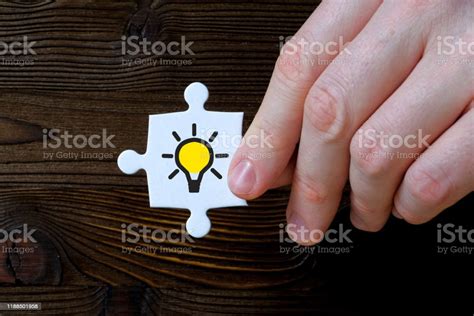 손에는 나무 배경에 노란색 조명이 있는 전구이미지가 있는 흰색 퍼즐 조각이 있습니다 태어난 아이디어의 개념 기회에 대한 스톡 사진 및 기타 이미지 Istock
