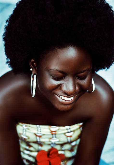 자연스러운 머리카락과 화려한 드레스를 입은 웃는 여성 · 무료 스톡 사진