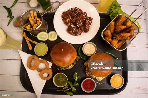 브리오슈 치킨 데리야끼 버거 스매시 더블 비프 치즈 버거 치킨 버팔로 윙 감자 튀김 웨지 라임 테이블에 분리 된 양파 링 모듬 패스트 푸드 0명에 대한 스톡 사진 및 기타