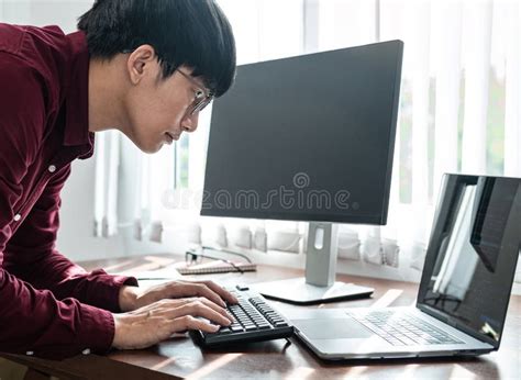 Asian Programmer Woman Looking On Multiple Computer Screen To Typing
