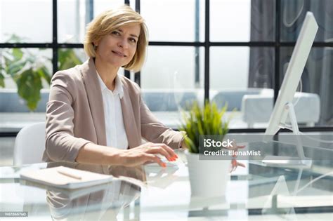 현대 데스크톱 컴퓨터를 사용하여 사무실에서 일하는 매력적인 중년 여성 경영자에 대한 스톡 사진 및 기타 이미지 경영자