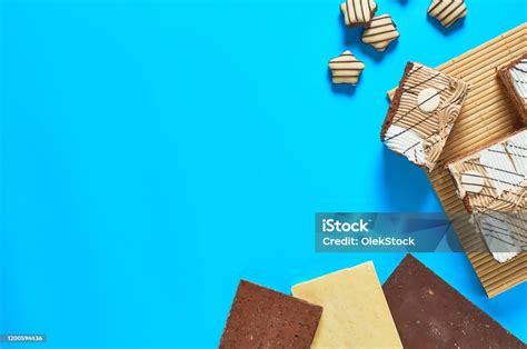 초콜릿 바와 사탕 근처 대나무 매트에 슬라이스 체크 무늬 직사각형 케이크는 파티의 파란색 테이블에 놓여있다 축 하 개념입니다 텍스트의 공백입니다 맨 위 보기 공휴일에 대한