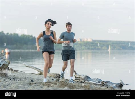 Cheerful Hispanic Caucasian Couple Running On Beach At Morning Stock
