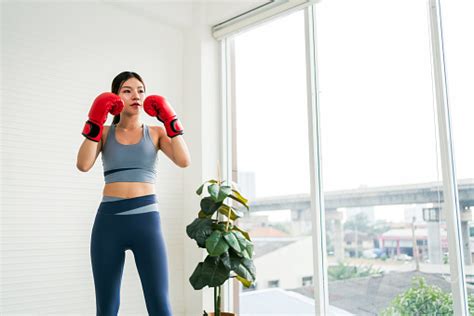 밝은 홈 체육관에서 권투 글러브를 끼고 훈련하는 여자 복싱 운동 자기 방어 피트니스 유산소 운동 근력 운동 무술 가정 운동 및 활동적인 라이프스타일과 같은 개념에 적합합니다