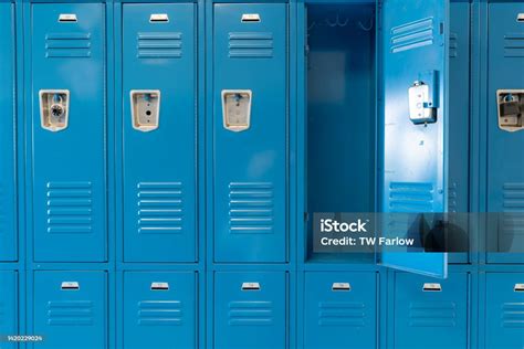 전형적인 미국 고등학교의 뚜렷하지 않은 복도를 따라 빈 파란색 금속 사물함을 하나씩 엽니 다 식별 가능한 정보가 포함되어 있지 않으며 홀에 아무도 없습니다 사물함에 대한