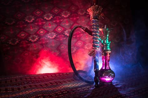 물 담 뱃 대 아라비아 내부에서 증기의 구름을 만드는 Shisha 그릇에 뜨거운 불길 오리엔탈 장식 카펫입니다 백라이트와 함께 어둠 속에 세련 된 동양 동아입니다 동아