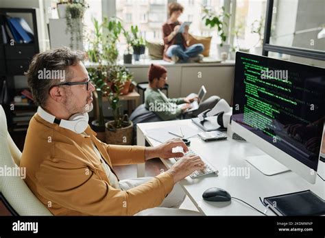Confident Mature Businessman Looking At Coded Data On Computer Screen