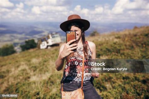 맑은 산 위에 Selfie 하 고 전화를 들고 바람 머리와 모자에 세련 된 여행자 소녀 여행과 방 랑 벽 개념입니다 텍스트를 위한 공간입니다 놀라운 대기 순간 개념에 대한