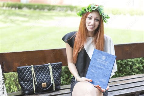 Portrait Of A Beautiful Redhead Girl Holding Her University Final Exam With A Laurel Wreath On
