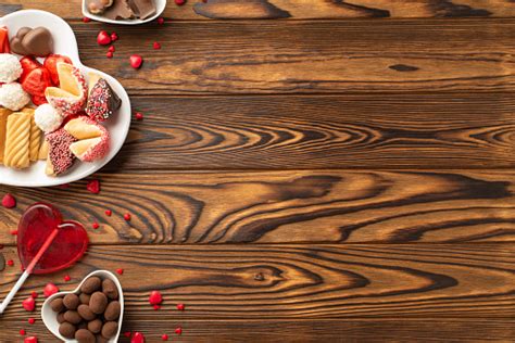 발렌타인 데이 축하 개념입니다 빈 공간이 있는 나무 책상 배경에 과자 초콜릿 젤리 사탕 롤리팝과 패스트리가 있는 하트 모양의 접시의 상위 뷰 사진 0명에 대한 스톡 사진 및