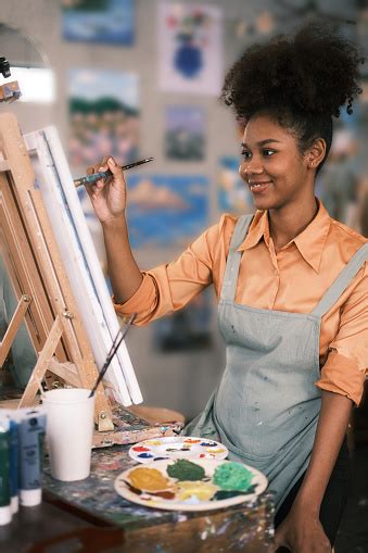 쾌활한 젊은 곱슬 미술 학교 여학생이 미술 스튜디오에서 캔버스에 붓으로 그림을 그렸다 여성에 대한 스톡 사진 및 기타 이미지 여성 화가 예술가 20 24세 Istock