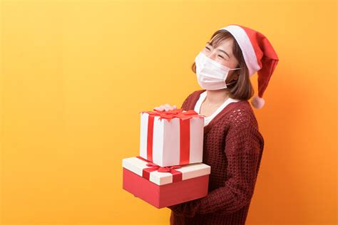 빨간 산타 클로스 모자 고립 노란색 배경 스튜디오를 입고 수술 마스크에 젊은 미소 여자의 초상화 12월에 대한 스톡 사진 및 기타 이미지 Istock