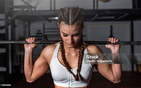 젊은 땀이 강한 근육 맞는 소녀 와 큰 근육 들고 바벨 뒤에 그녀의 머리 준비 하 고 하드 스쿼트 운동 훈련에 대 한 집중 에 무거운 무게 에 체육관 닫아 여자에 대한 스톡