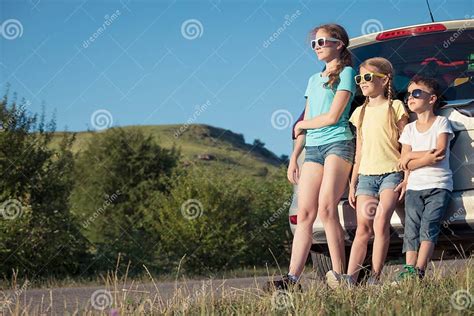 Счастливый брат и две его сестры стоят рядом с машиной днем Стоковое Фото изображение