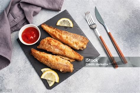 토마토 소스와 신선한 레몬 조각을 곁들인 생선 갈락 튀김 지방이 많은 패스트 푸드를 먹는 개념 회색 콘크리트 배경 복사 공간