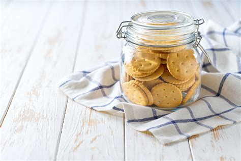 하얀 탁자 위에 맛있는 밀 둥근 크래커가 가득 담긴 항아리와 텍스트를 위한 복사 공간이 있습니다 짭짤한 둥근 크래커로 가득 찬 항아리의 클로즈업 건조한에 대한 스톡 사진 및