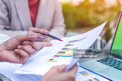 두 비즈니스 여성은 현대 노트북 컴퓨터와 소득 차트및 그래프를 검토하고 분석 그래프를 가리키는 비즈니스 여성 손가락을 닫습니다