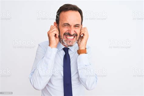 시끄러운 음악의 소음에 대한 성가신 표정으로 손가락으로 귀를 덮는 고립 된 흰색 배경 위에 우아한 넥타이를 입은 중년 사업가 청각 장애인 개념입니다 가리기에 대한 스톡 사진