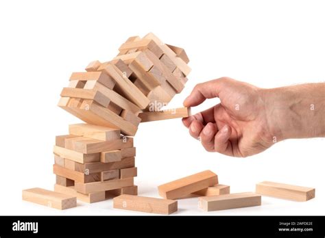 Businessman Removing Wooden Block From Falling Tower On Table